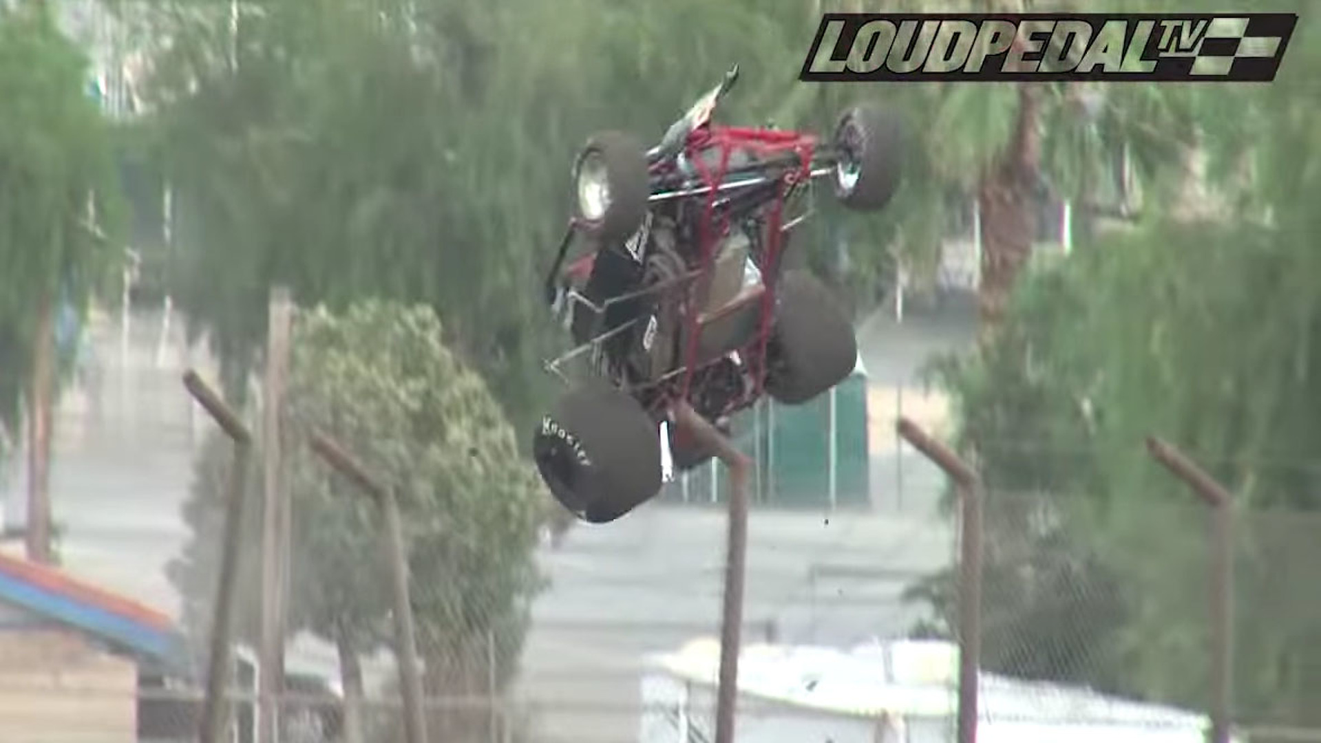 Driver walks away after flying over track's 22-foot fence